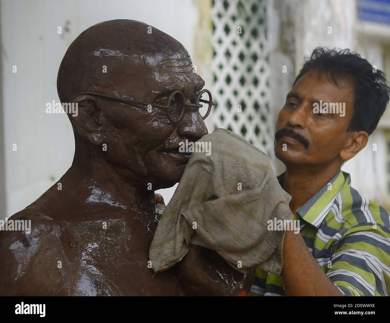 A worker is washing and cleaning the statue of Mahatma Gandhi on the ...