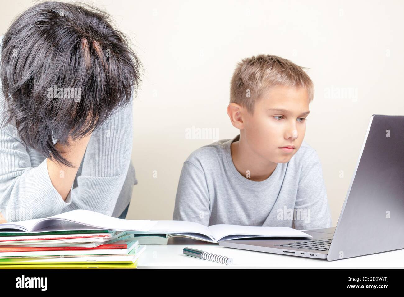Kid learning online with laptop computer. Mother help him, explains ...