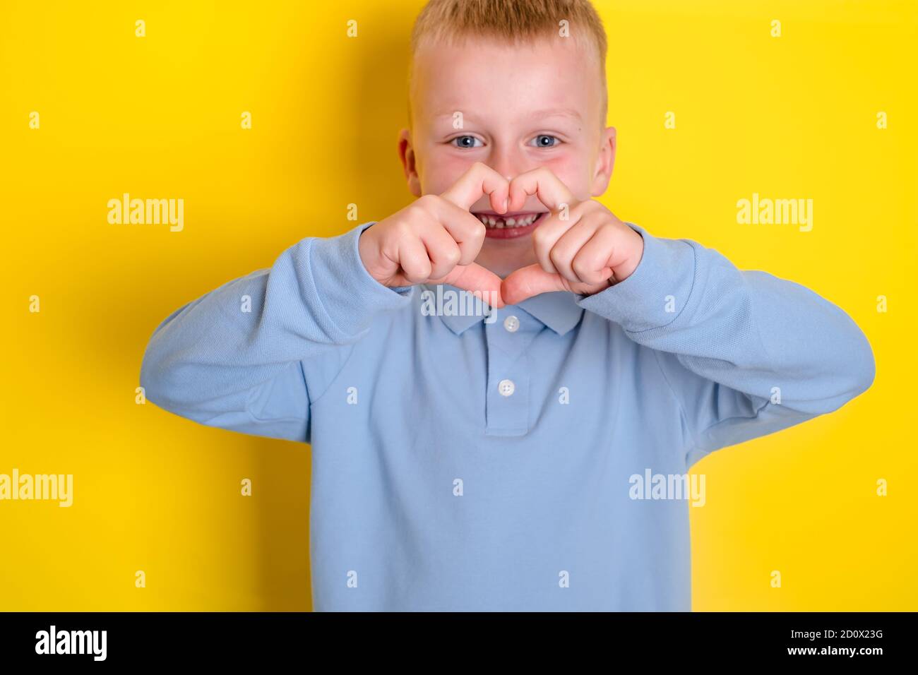 The child's hands show the heart, child smile without upper baby tooth ...