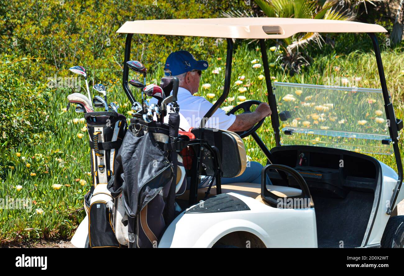 Happy senior men playing golf driving the golf cart or buggy on the ...