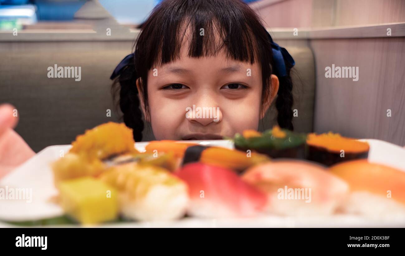 Asian little child girl eating sushi in a cafe Stock Photo - Alamy
