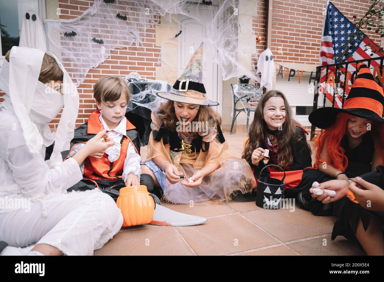 Children sharing and comparing their candies on Halloween sitting on a ...