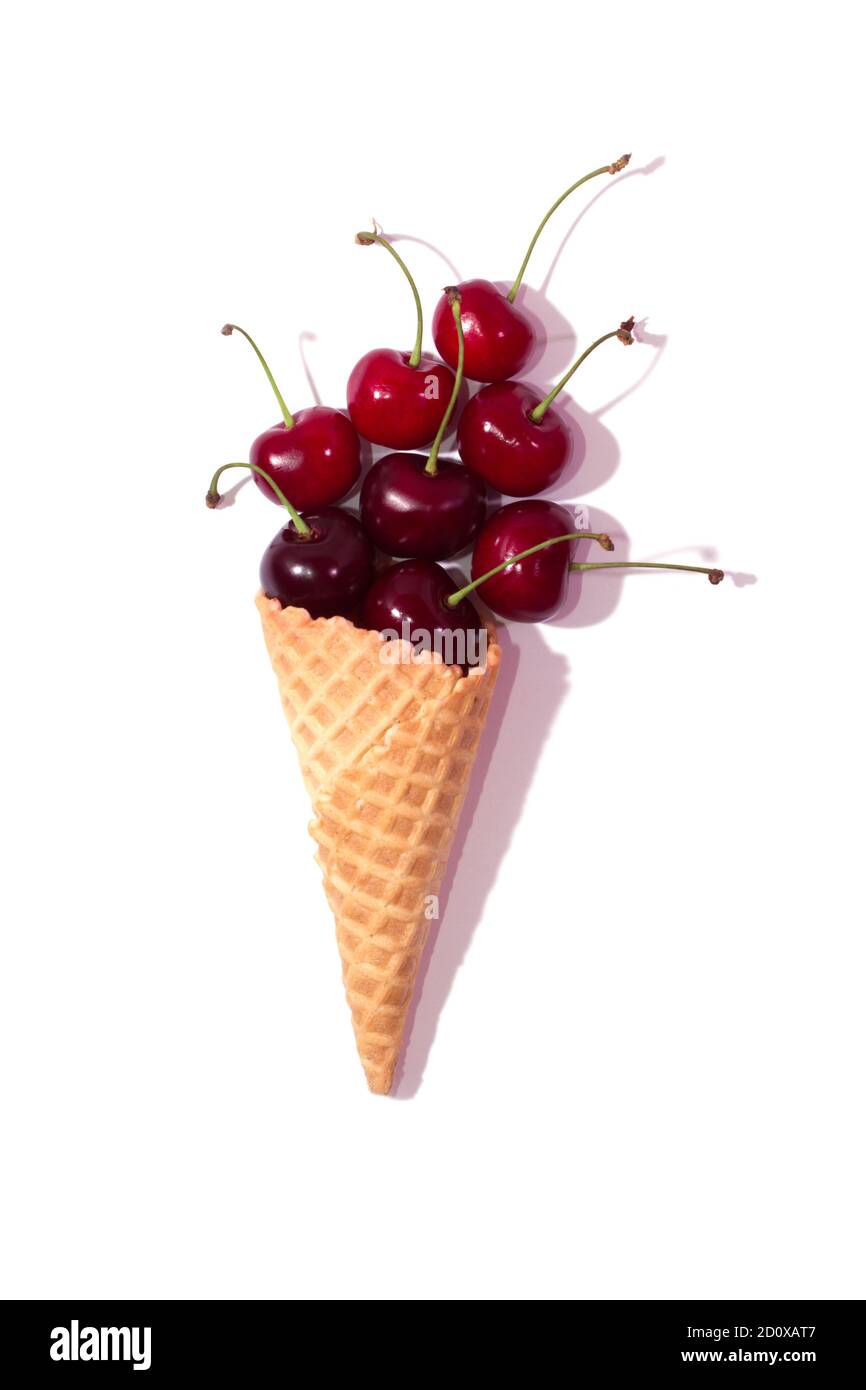 Conceptual art. Cherries in an ice cream cone on a table on a white ...