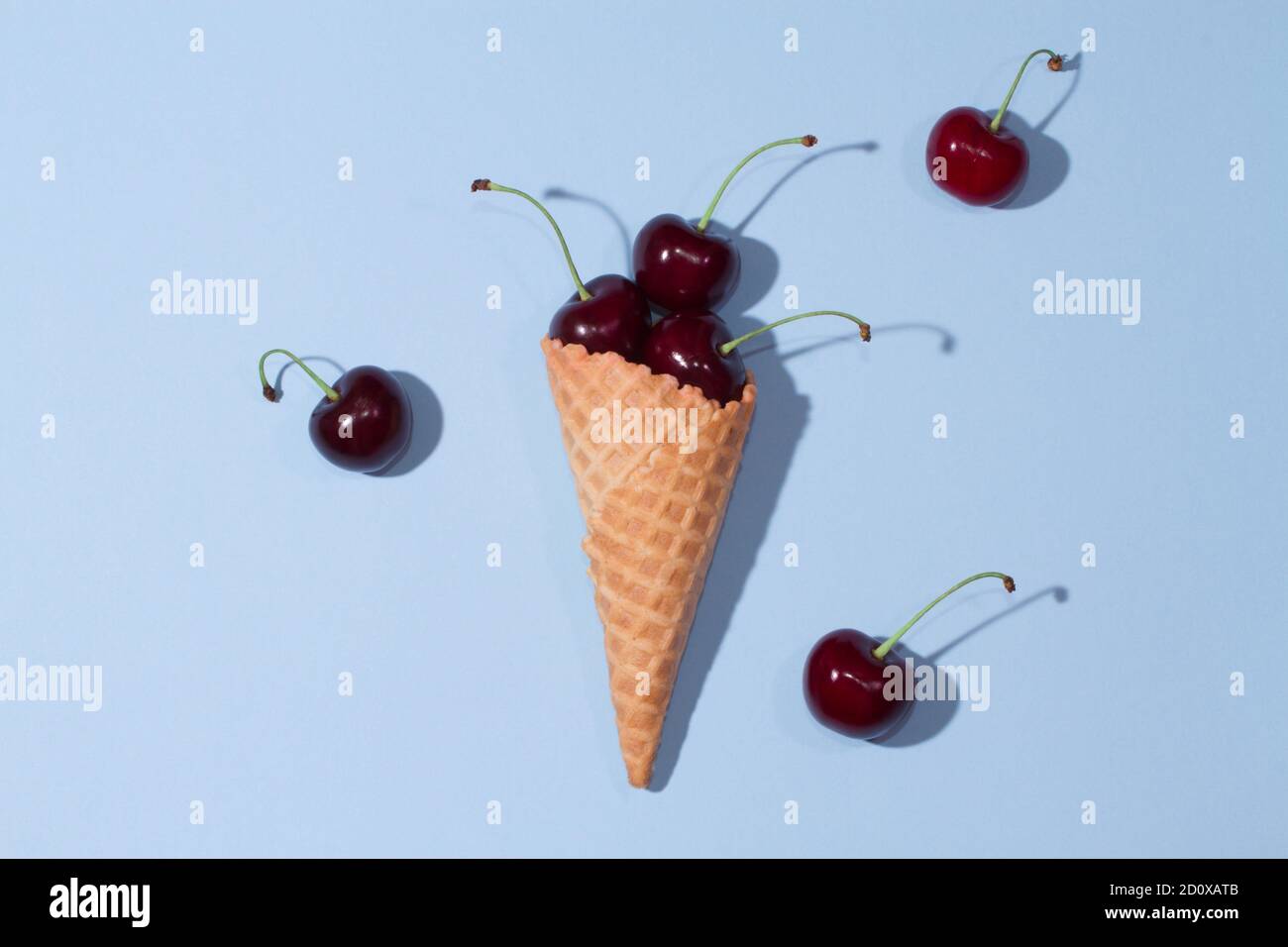 Conceptual art. Cherries in an ice cream cone on a table on a blue ...