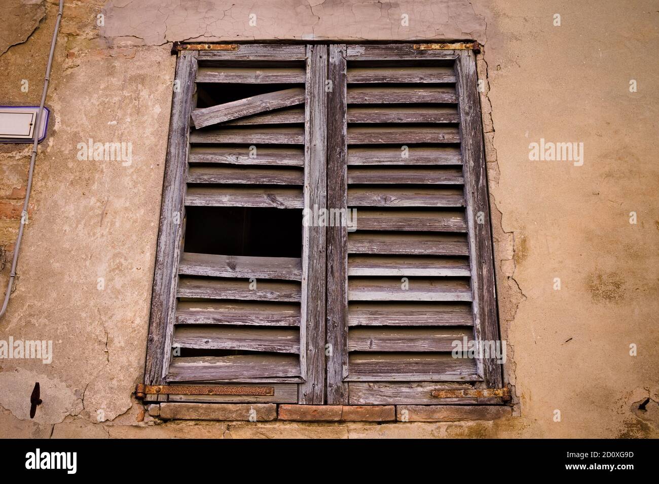 A ruined window with a broken wooden shutter in a medieval italian ...