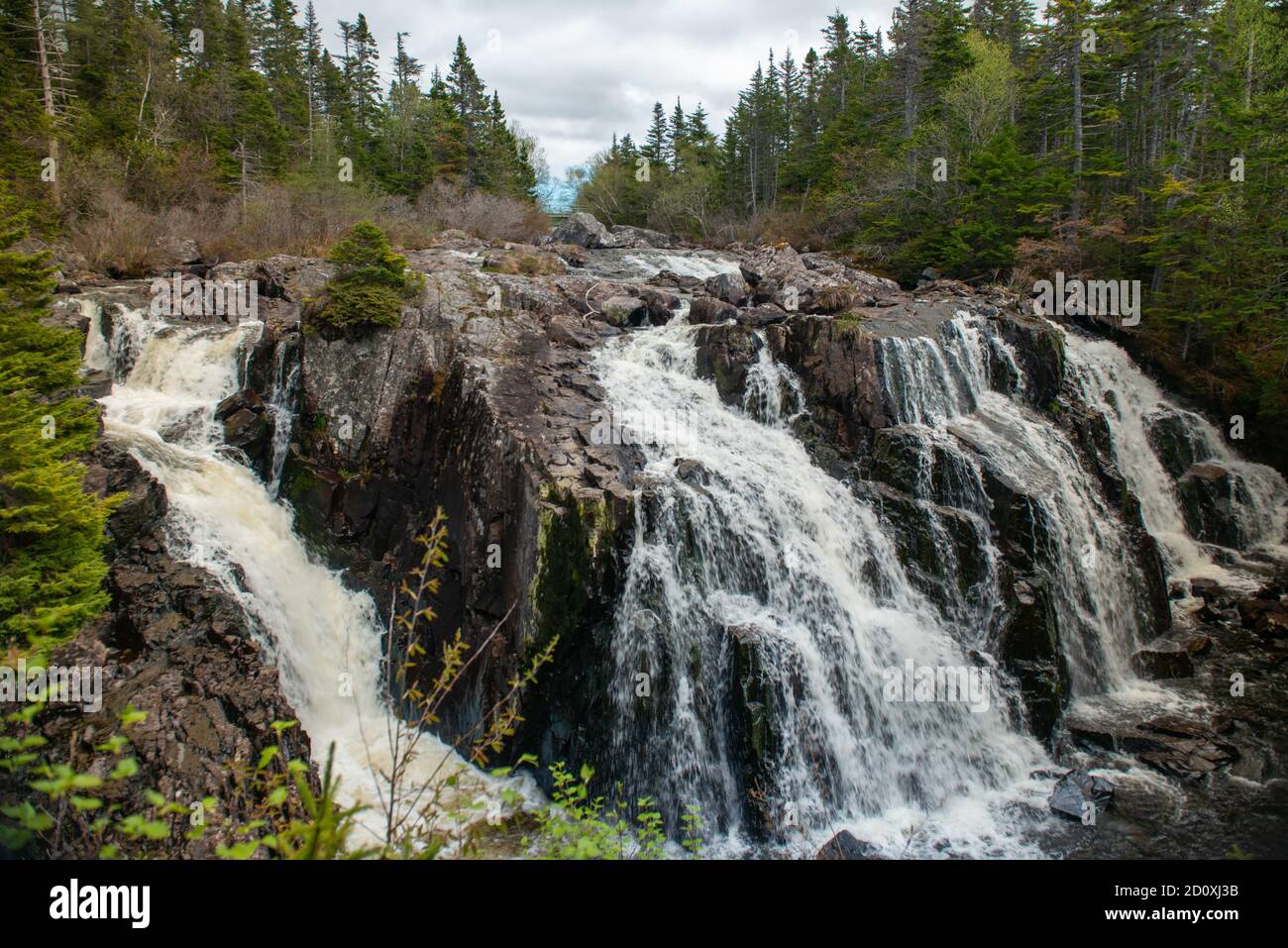 Multiple waterfalls of white rushing water falling over large rocks ...