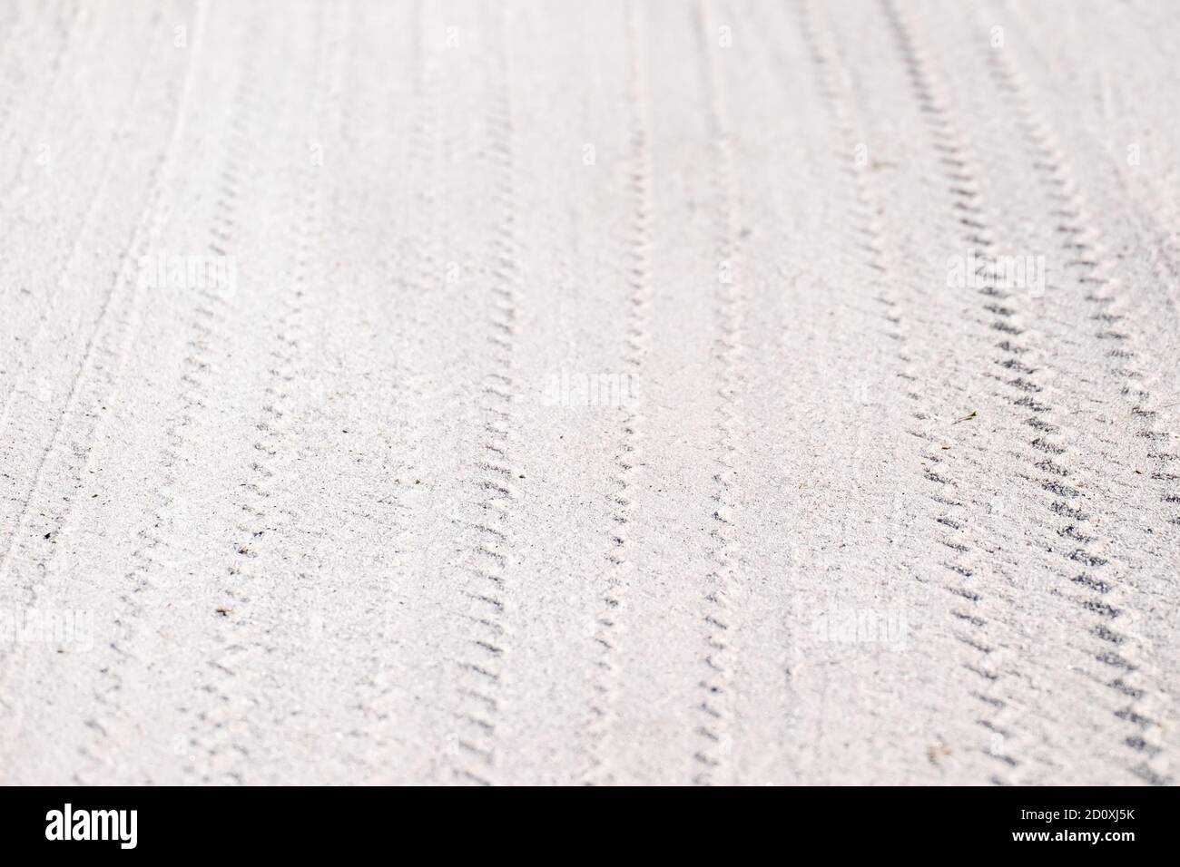 Vehicle tire patterns in white sand. The wheels have made a triangle ...