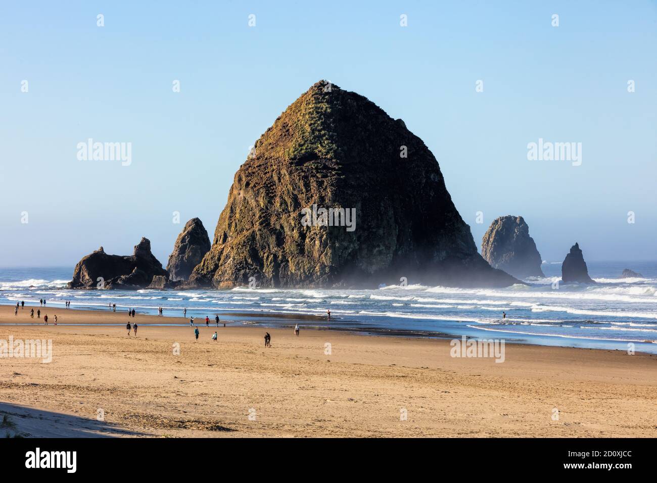 Low tide on the Oregon coast with people walking near Haystack Rock ...