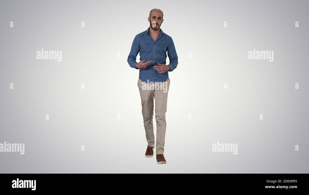 Arabic casual man walking and talking to camera on gradient back Stock ...