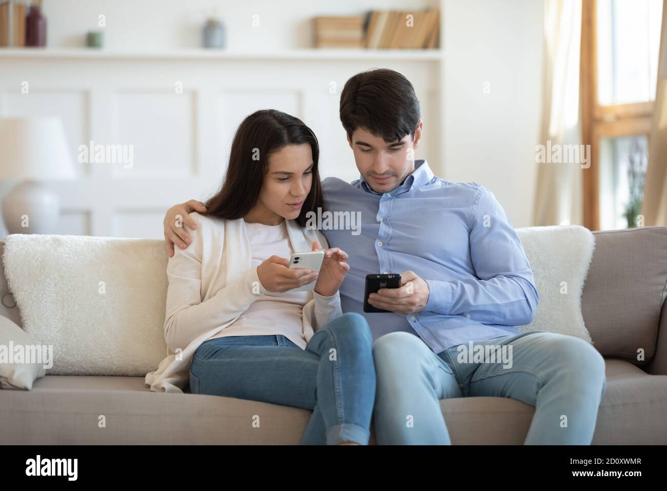 Young couple in love using gadgets together sharing interesting ...