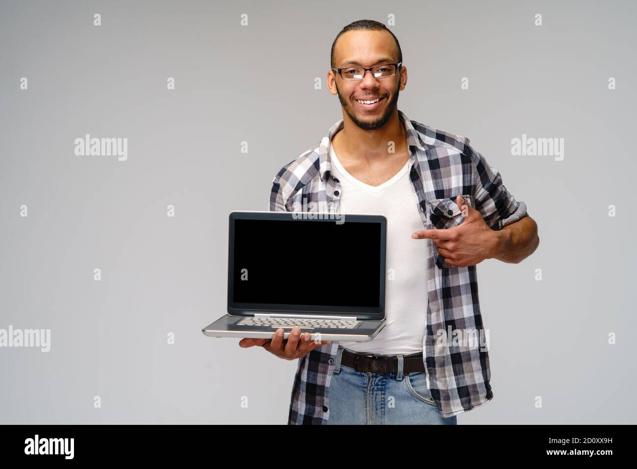 A young african american man holding laptop pc and showing at blank ...
