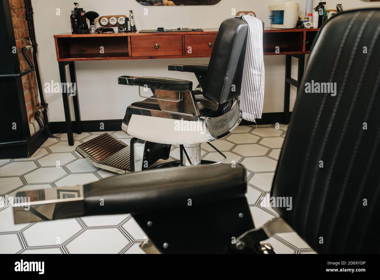 Adjustable chairs set up in a barber shop on hexagonal-patterned floor ...