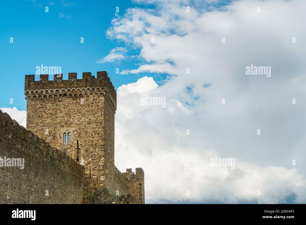 The square tower of an ancient fortress on a background of blue sky ...