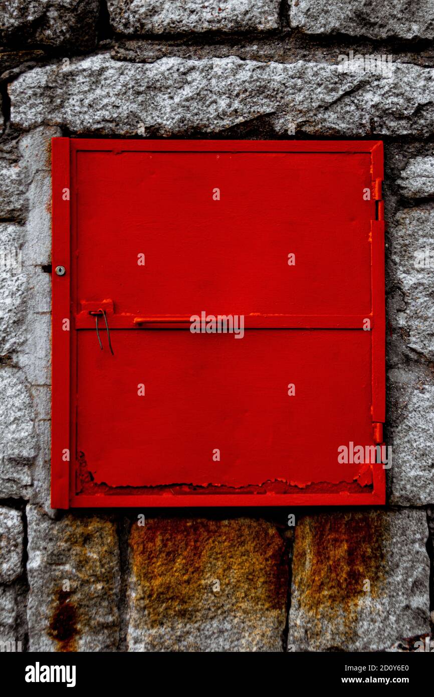 Closeup of a locked red steel door with rust on stonewall background ...