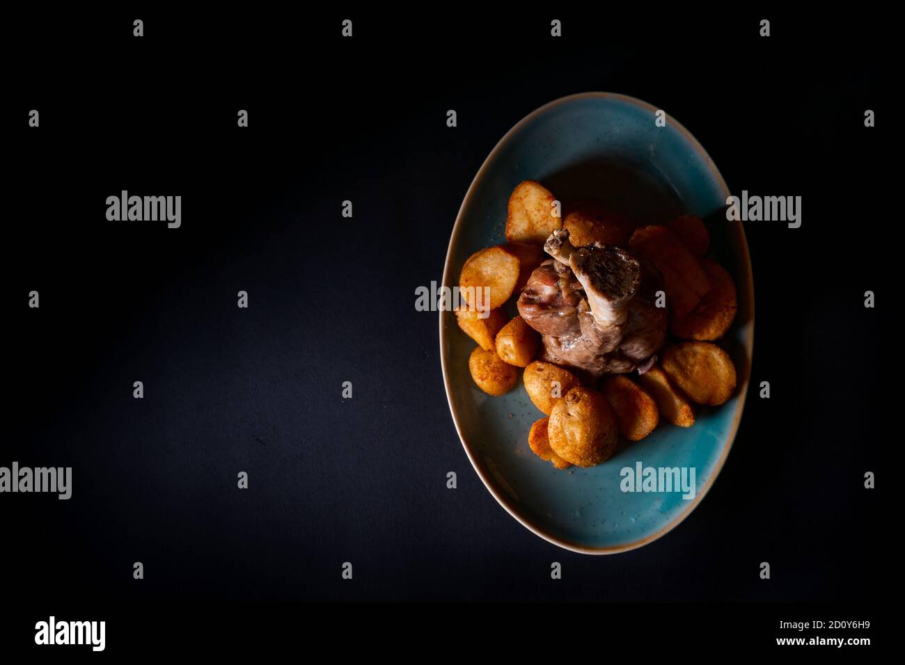 Lamb with potatoes on a plate on black background Stock Photo - Alamy