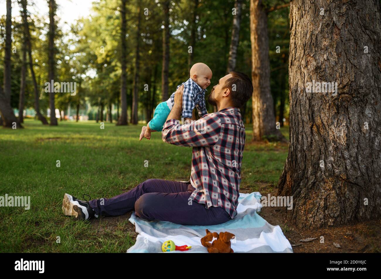 Father and his little baby sitting under the tree Stock Photo - Alamy