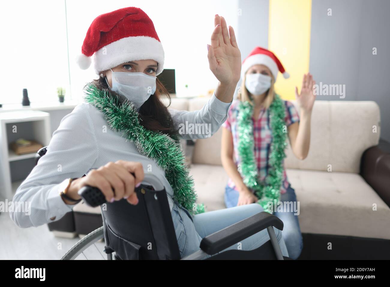Disabled woman in wheelchair in red santa claus hat waves her hand ...