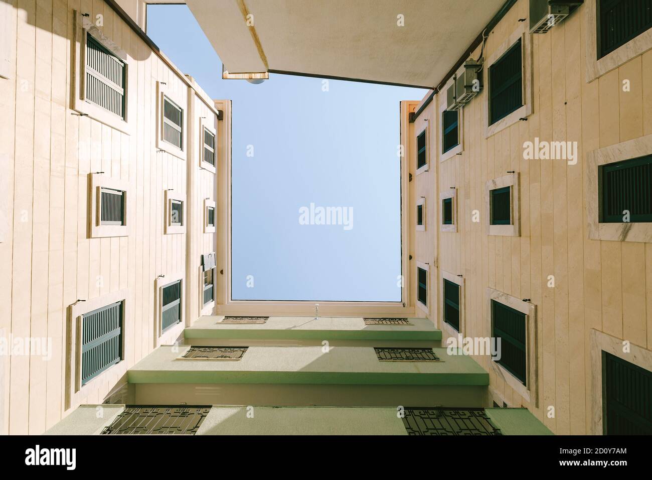 Bottom view of a tall building with closed windows and a piece of sky ...