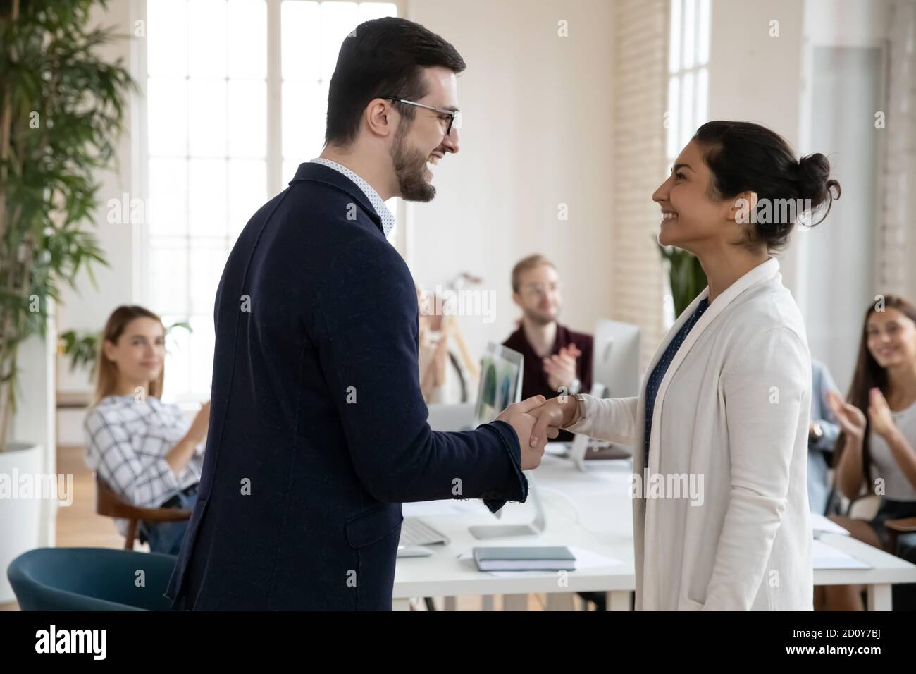 Smiling male boss handshake female colleague greeting with success ...