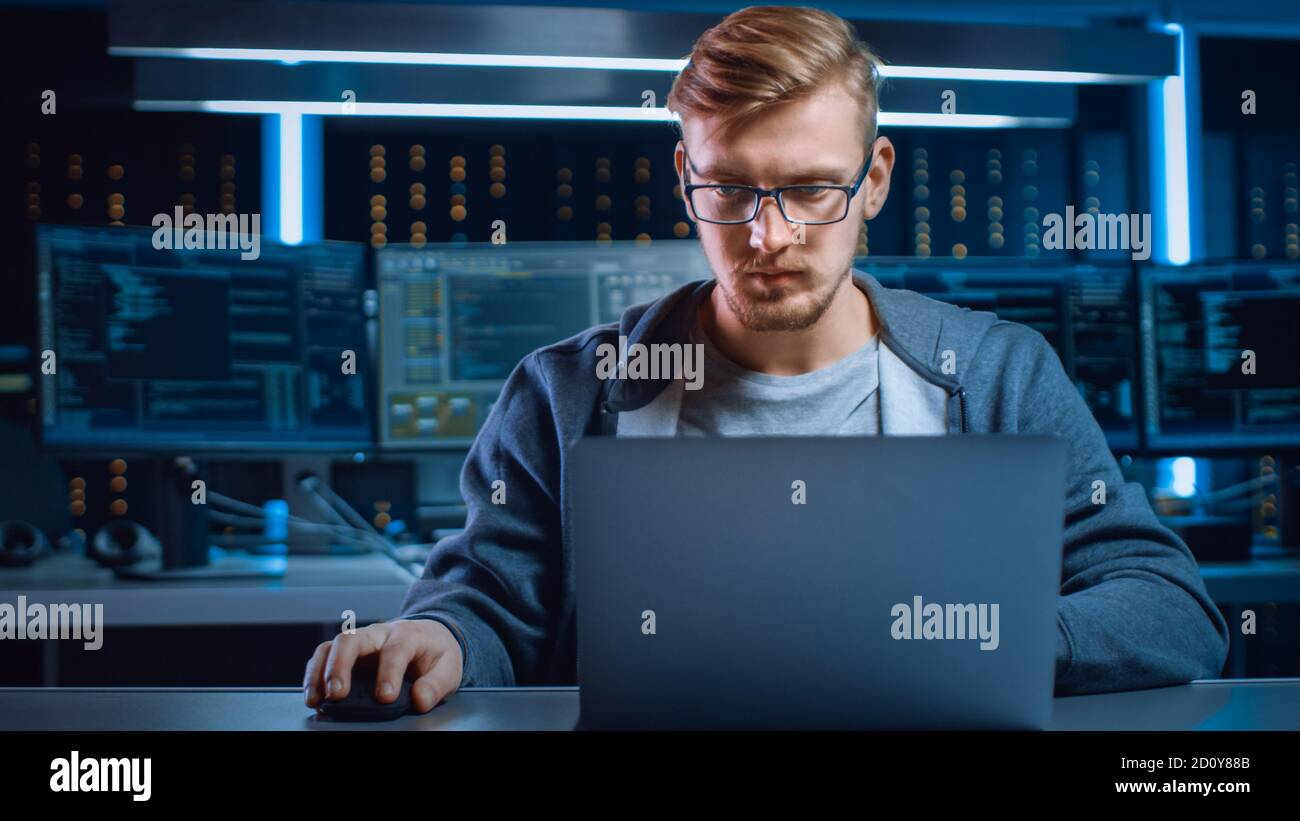 Portrait of Software Developer Hacker Wearing Glasses Sitting at His Desk and Working on ...