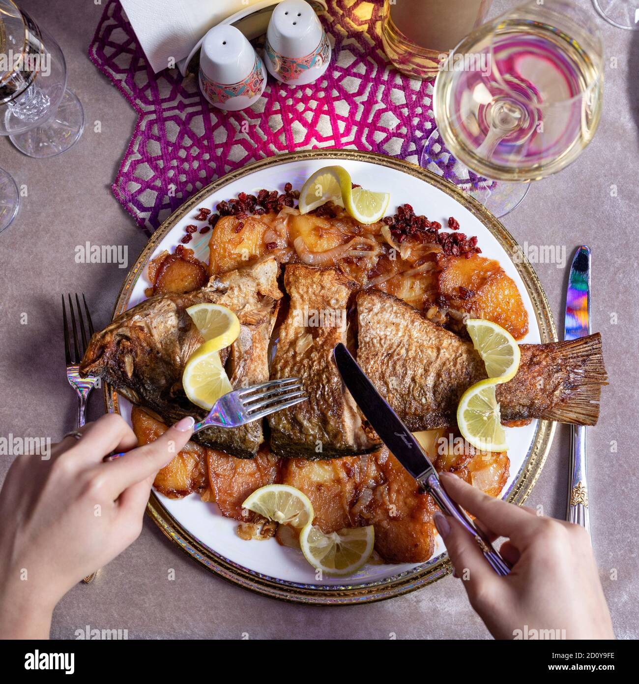 Woman eating a grilled whole fish with a lemon top view Stock Photo - Alamy