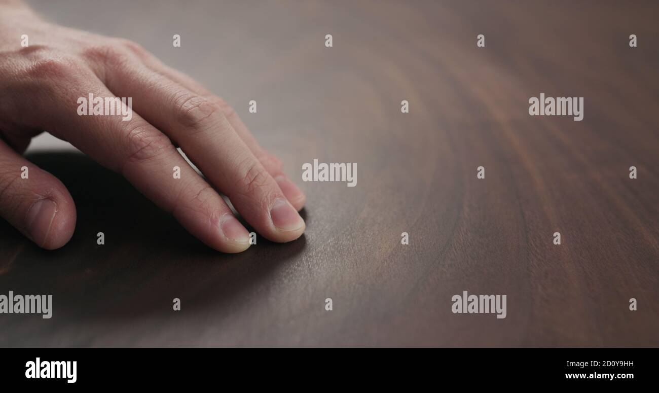 man hand checking toned walnut table surface with oil finish, wide ...