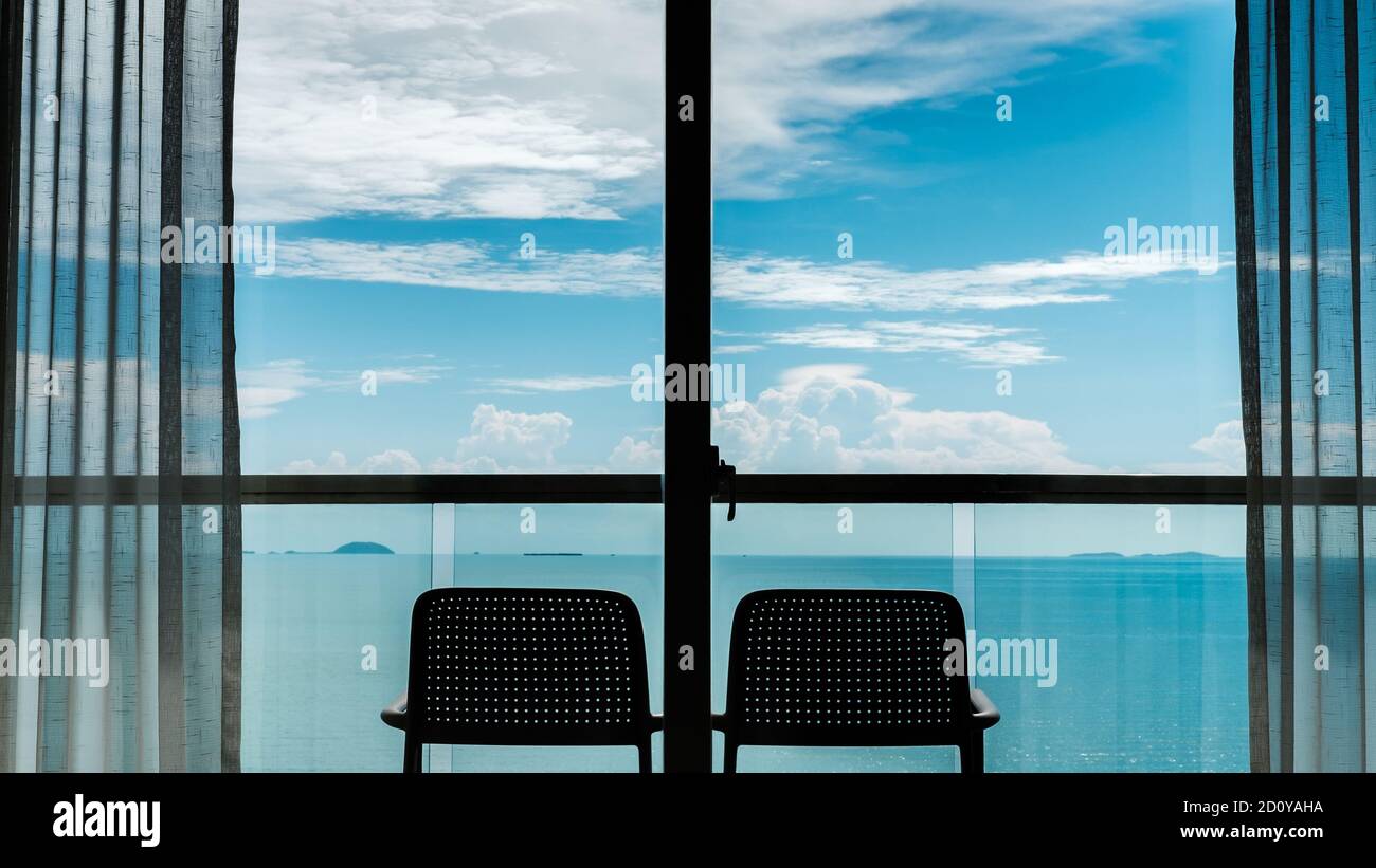 Back view from the window of 2 chairs on the balcony, sea and sky views ...