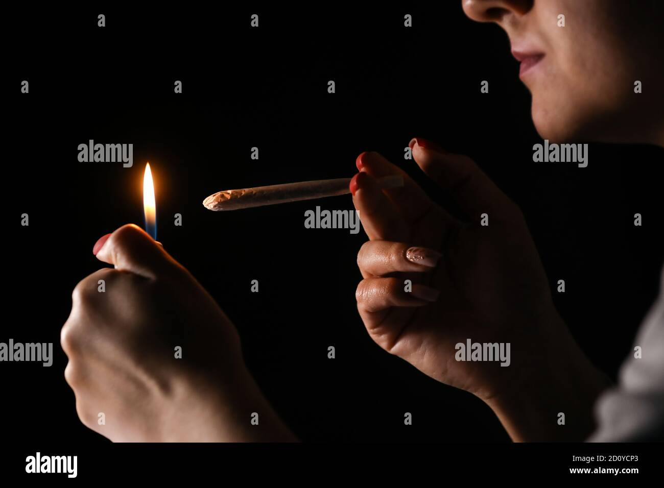 Woman hand holding cigarette in a smoke against black background ...