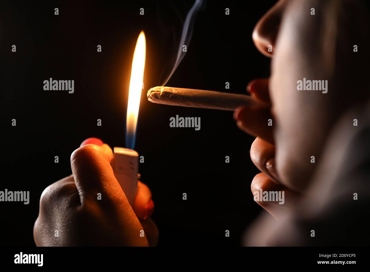 Woman hand holding cigarette in a smoke against black background ...