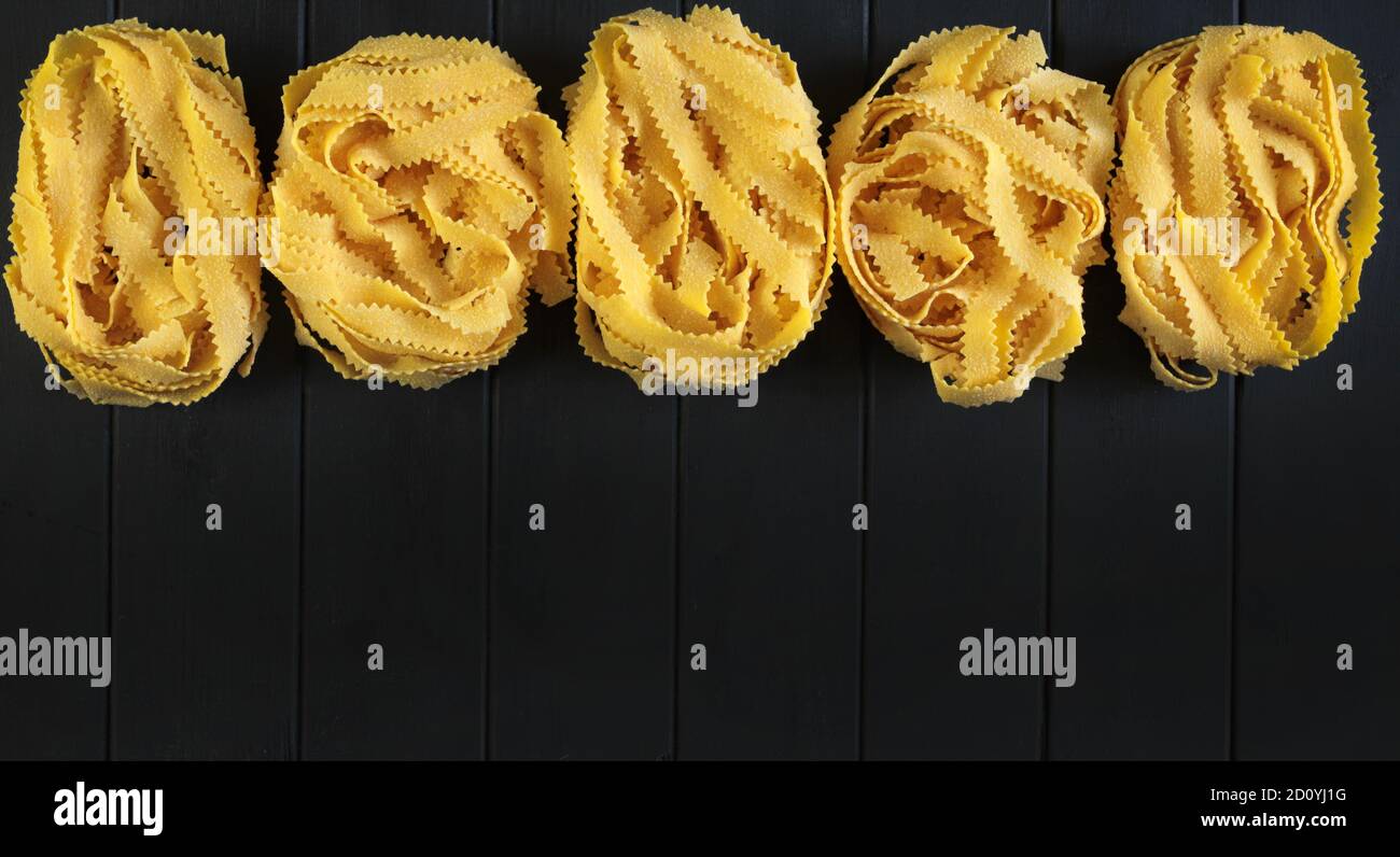 Italian pasta. Curly pappardelle pasta on dark background. View from ...
