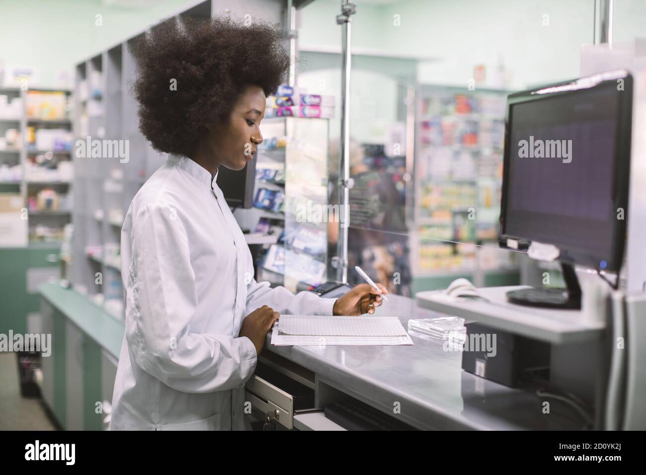 Portrait of young professional concentrated African female pharmacist ...