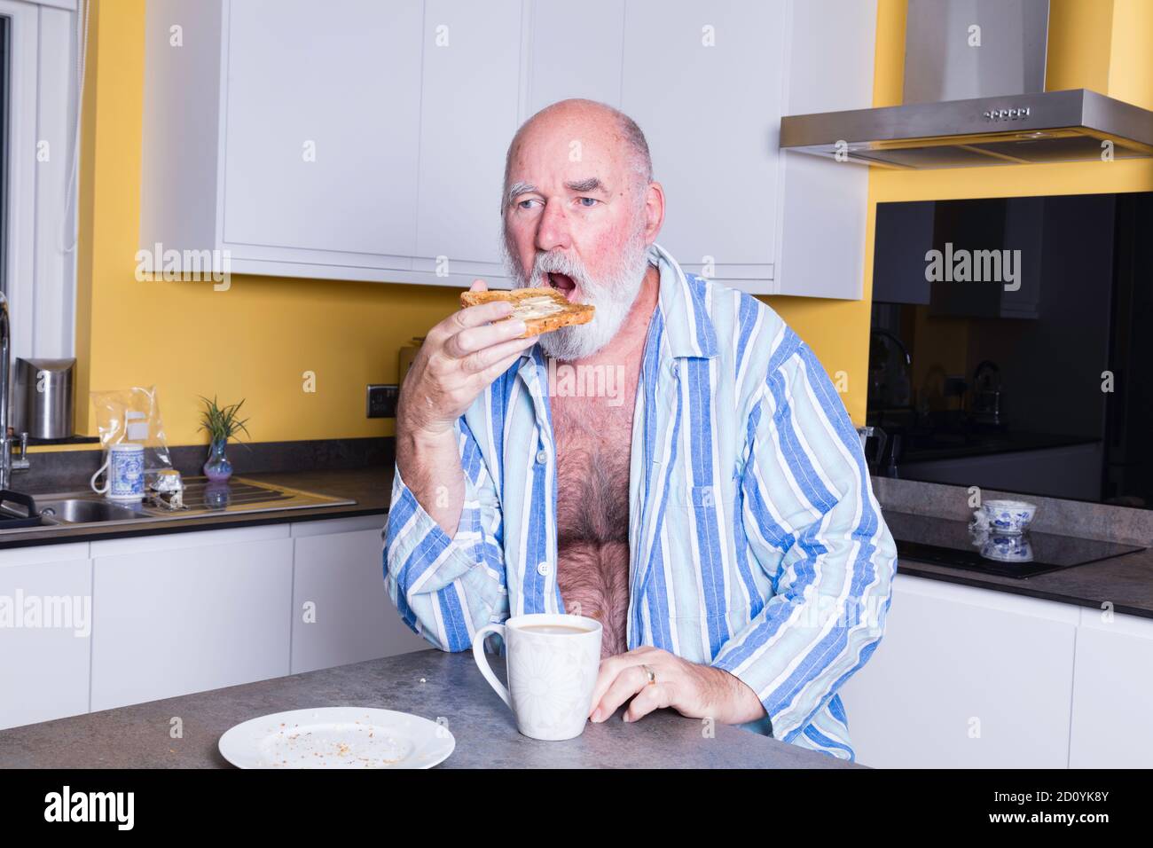 Old man in his pyjamas enjoying his breakfast toast and a cuppa Stock ...