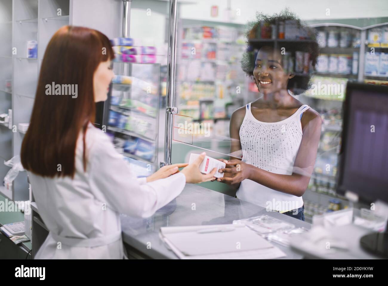 Back view of beautiful young Caucasian pharmacist selling medications ...