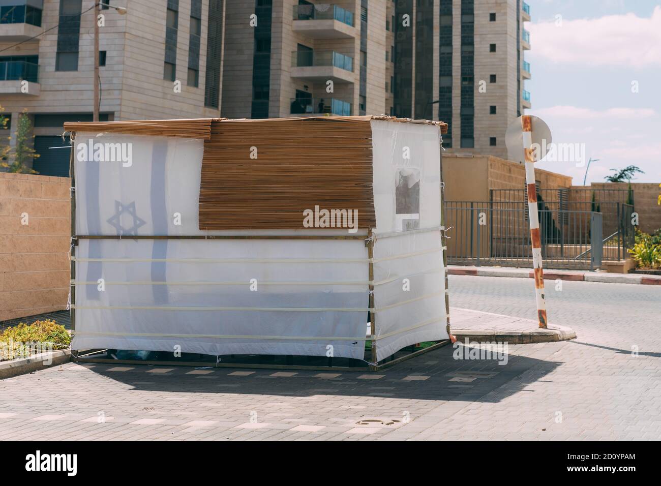 One white Sukkah outside on the street with israeli flag inside near ...
