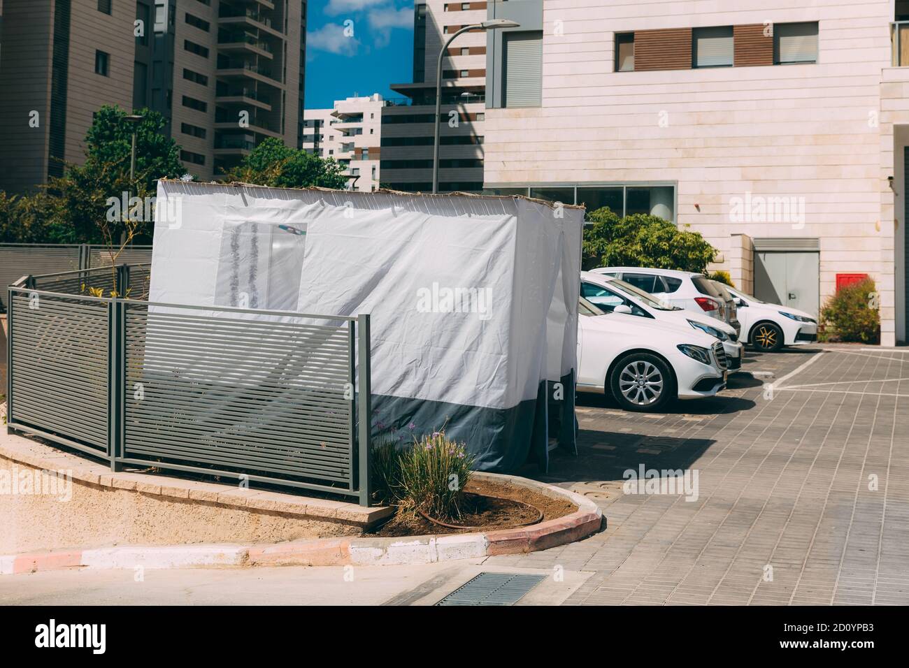 One white blue Sukkah outside on the street with cars near buildings, a ...