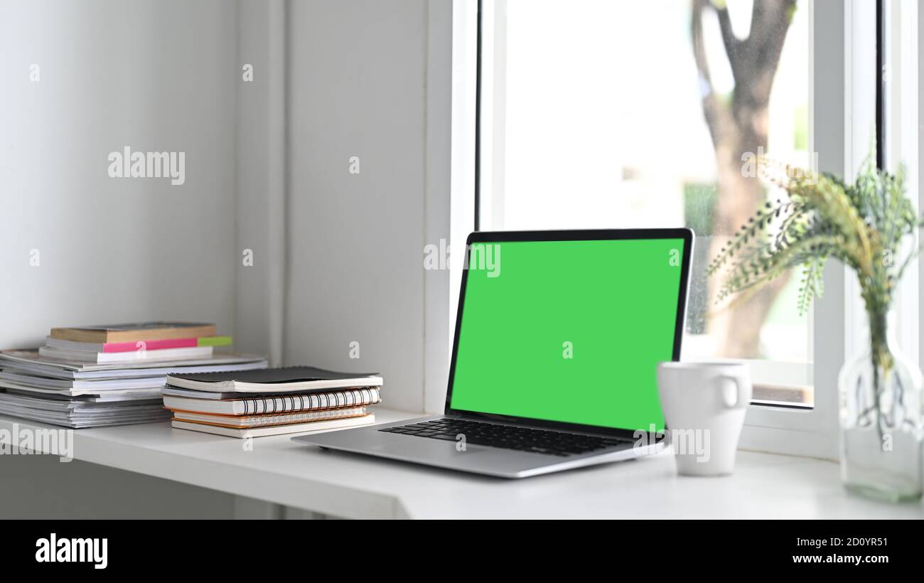 Side view laptop computer with green screen and office supplies on ...