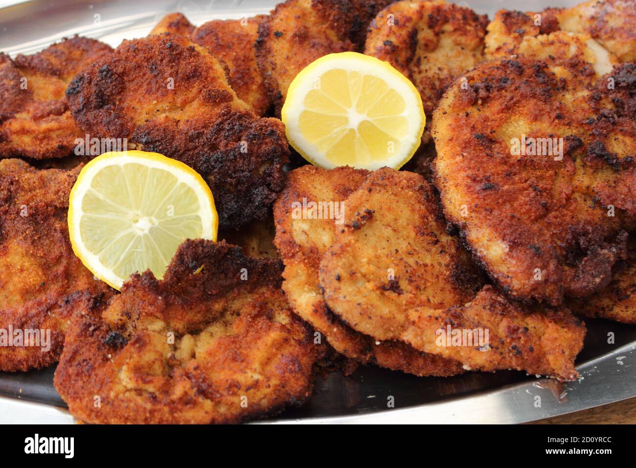 lots of crispy fried Viennese schnitzel with lemon Stock Photo - Alamy