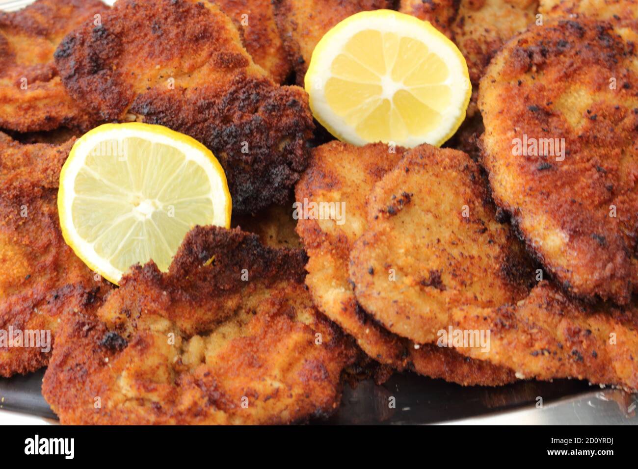 lots of crispy fried Viennese schnitzel with lemon Stock Photo - Alamy