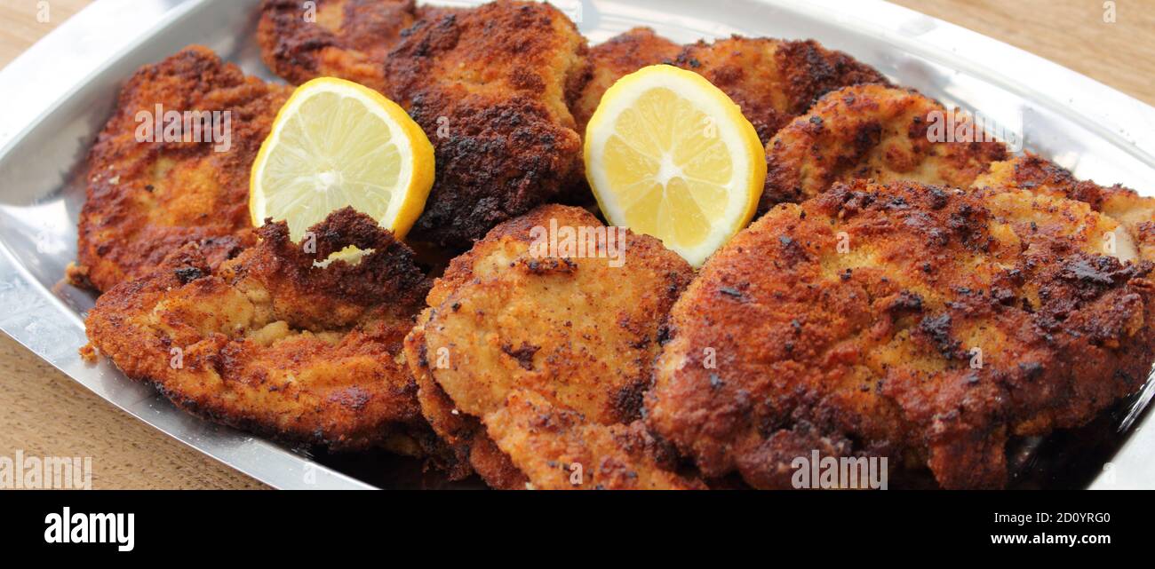 lots of crispy fried Viennese schnitzel with lemon Stock Photo - Alamy