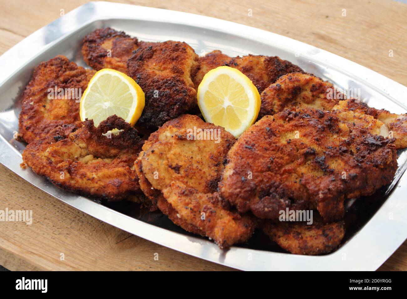lots of crispy fried Viennese schnitzel with lemon Stock Photo - Alamy