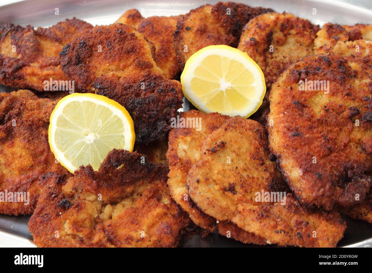 lots of crispy fried Viennese schnitzel with lemon Stock Photo - Alamy