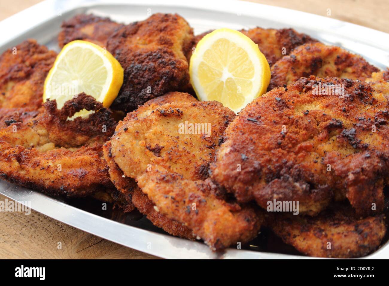 lots of crispy fried Viennese schnitzel with lemon Stock Photo - Alamy