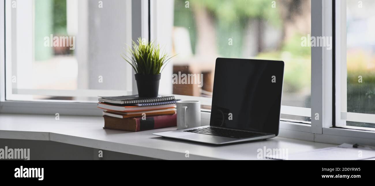 Laptop with a black screen is putting on a windowsill surrounded by ...