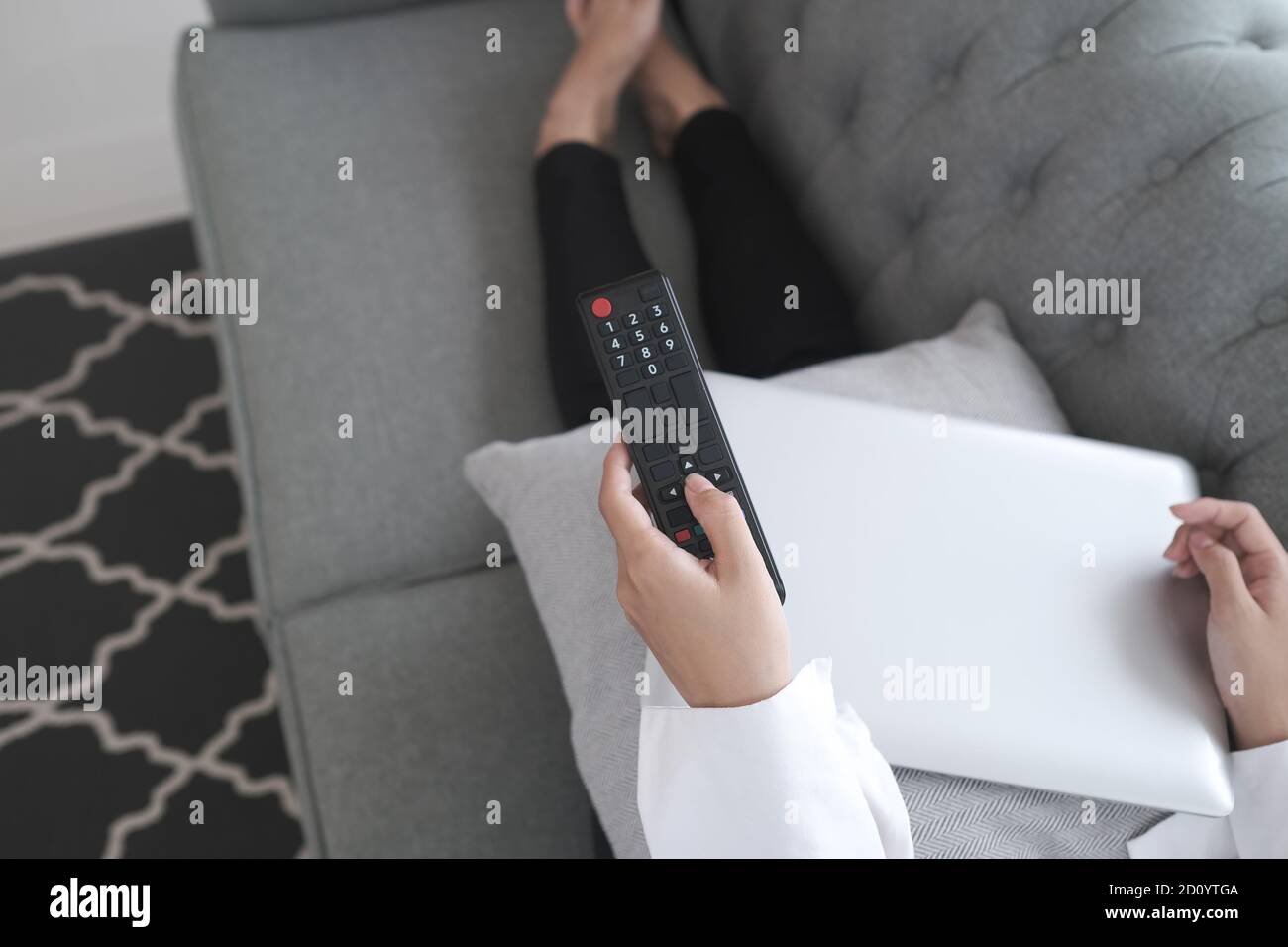 Close up of woman sitting on couch while switching TV channels hand ...