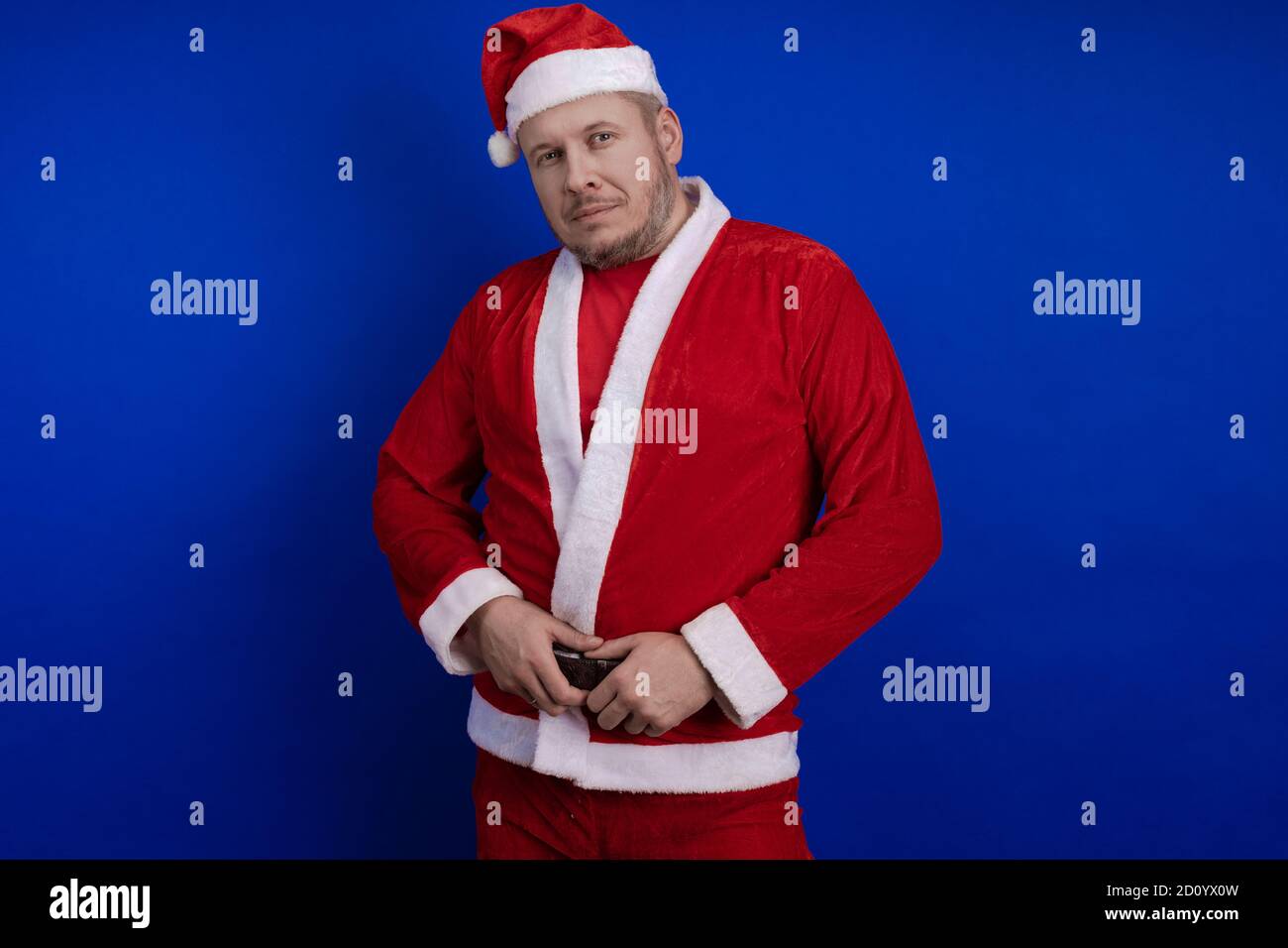 Male actor in costume and hat of Santa Claus posing on a blue ...
