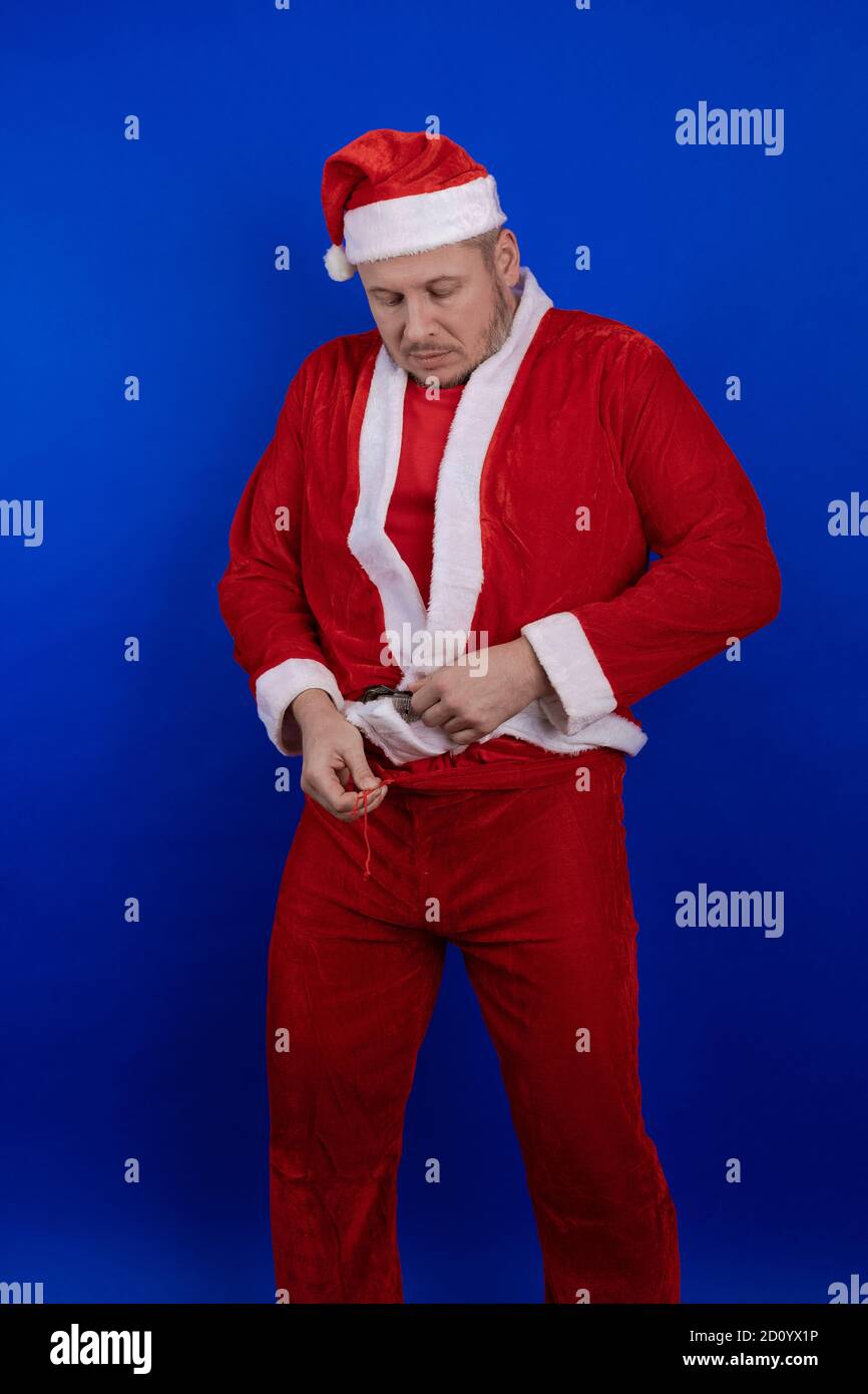 Male actor in costume and hat of Santa Claus posing on a blue ...