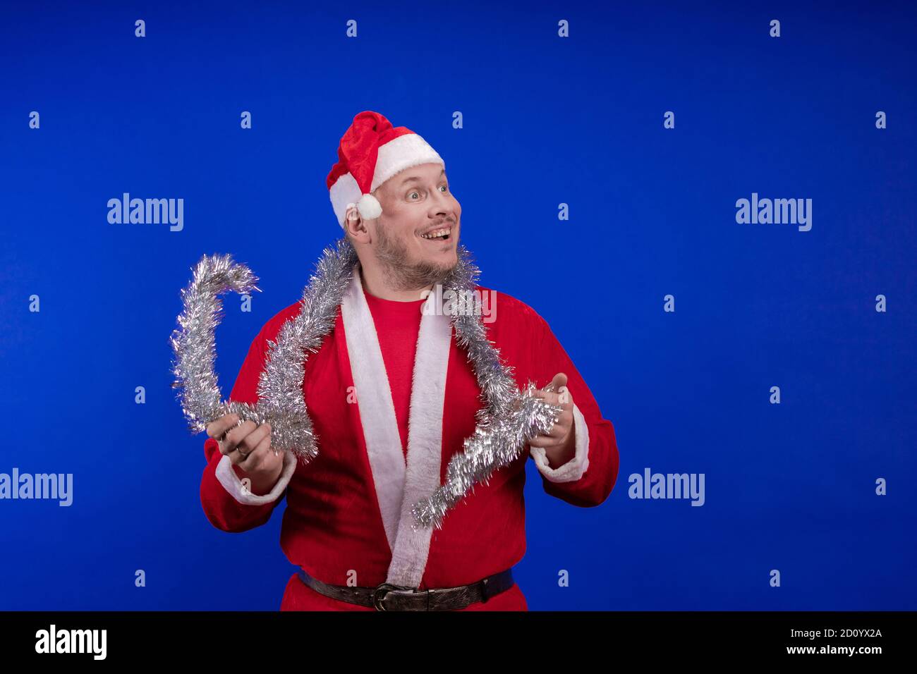 Male actor in a suit and hat of Santa Claus with a silver tinsel ...