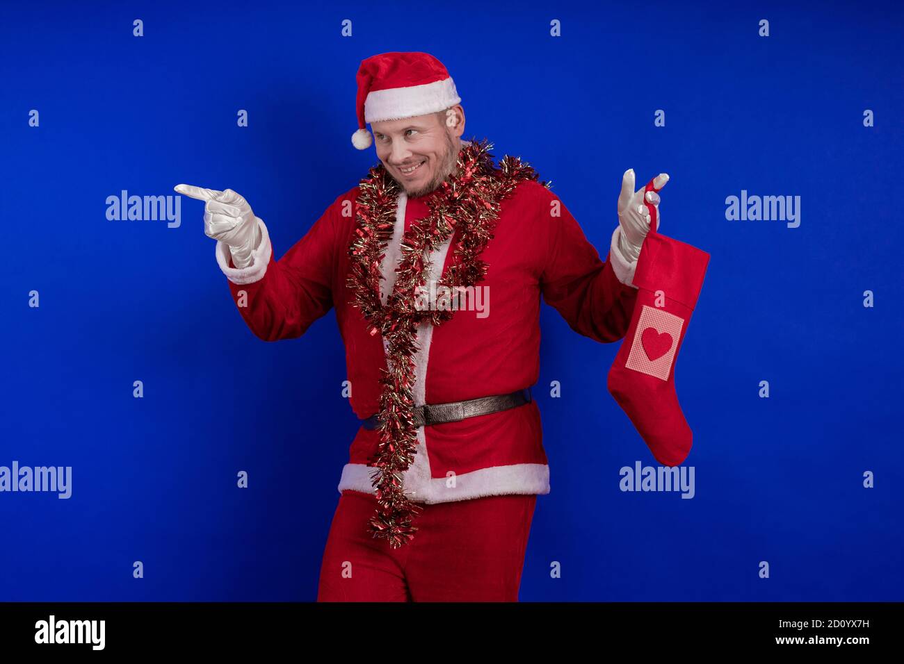 Emotional male actor in a costume of Santa Claus holds a Christmas sock ...