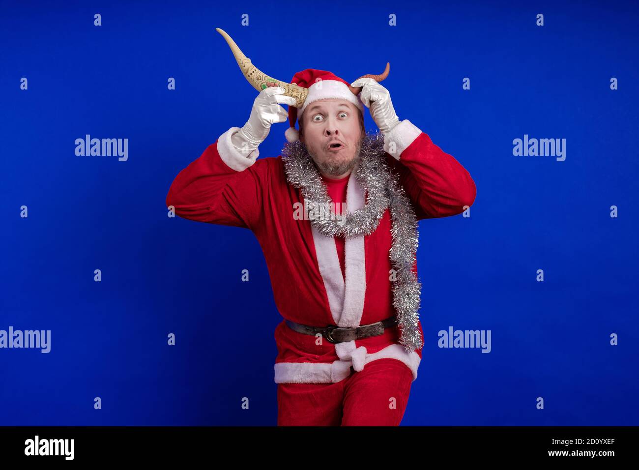 Male actor in a costume of Santa Claus holds horns, jokes, grimaces and ...