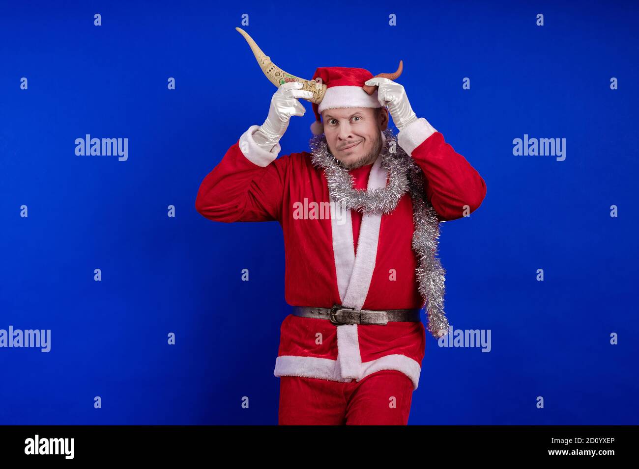 Male actor in a costume of Santa Claus holds horns, jokes, grimaces and ...